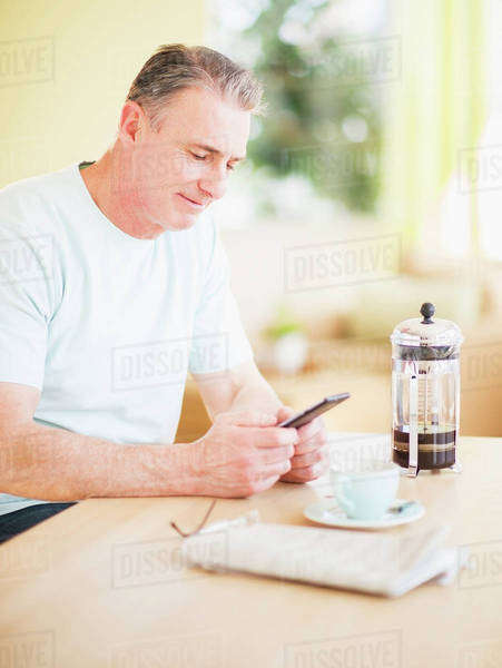 Portrait of man at kitchen table using mobile phone - Stock Photo ...