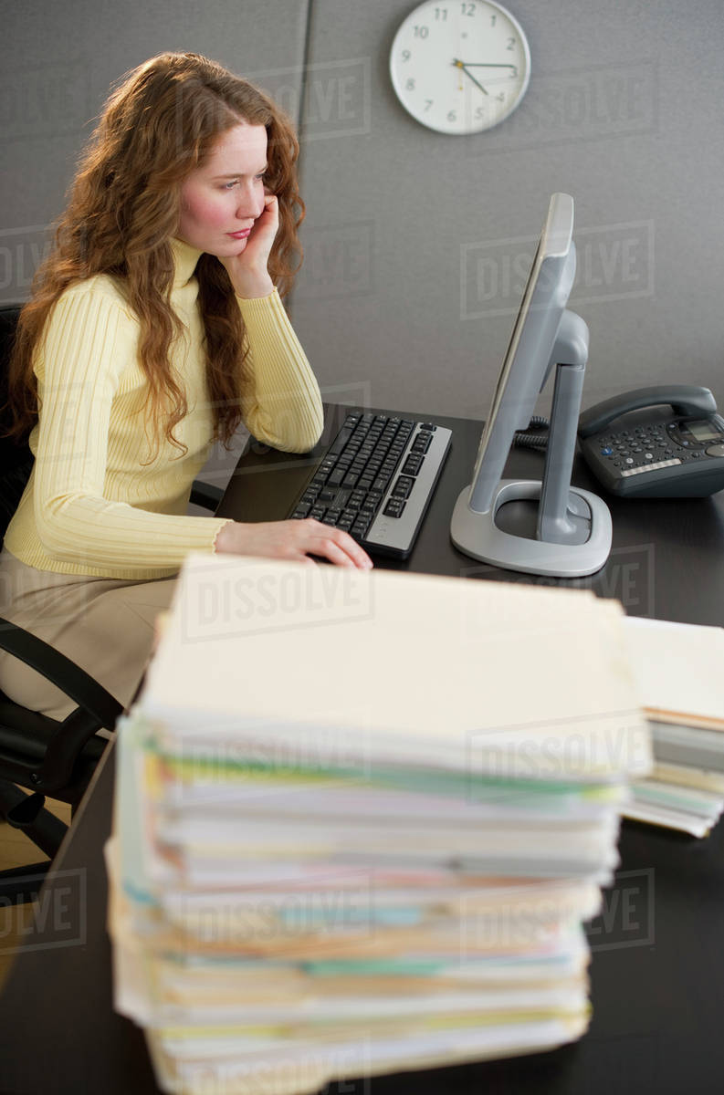 Overworked woman in cubicle - Stock Photo - Dissolve