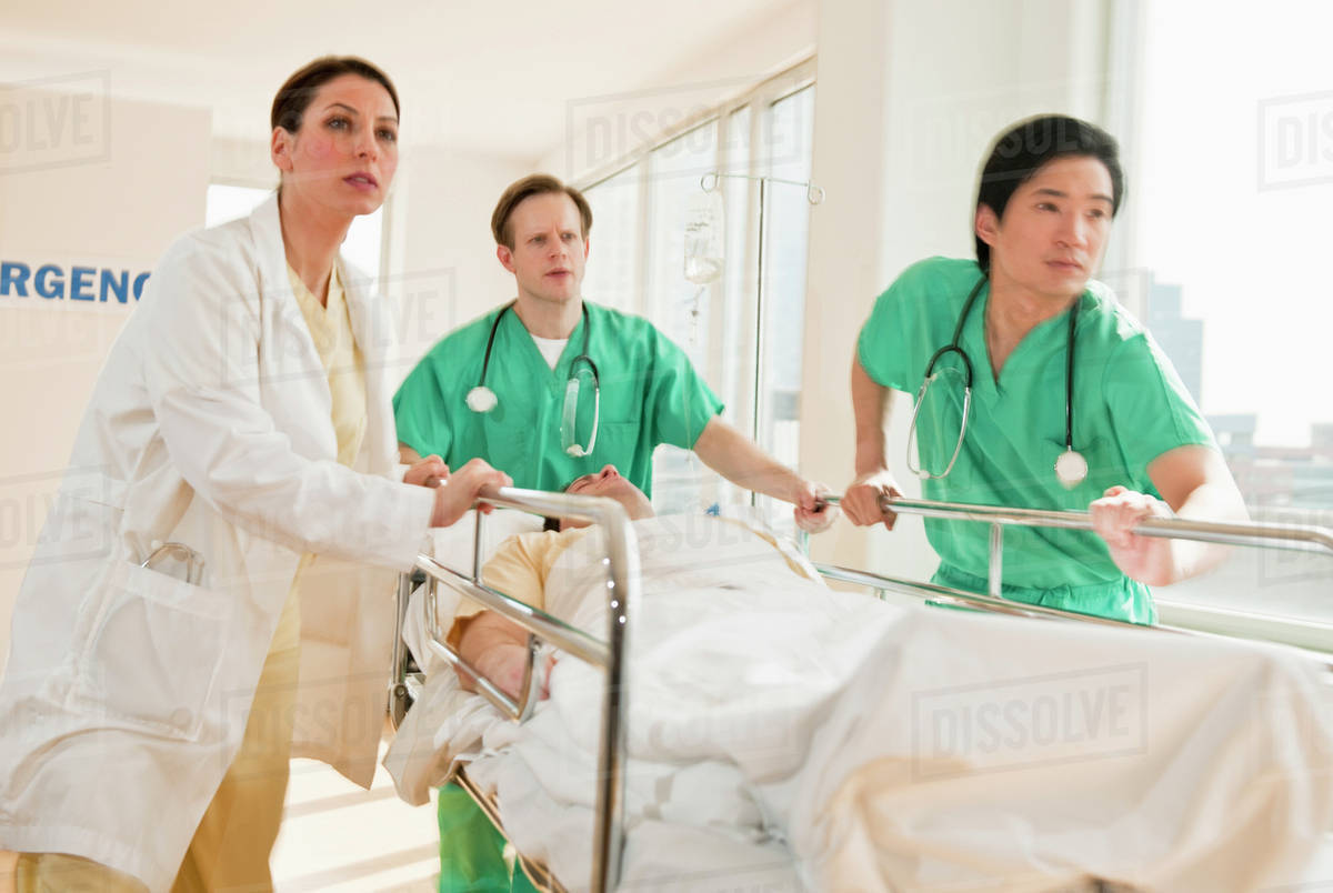 Healthcare workers pushing gurney in emergency room - Royalty-free ...