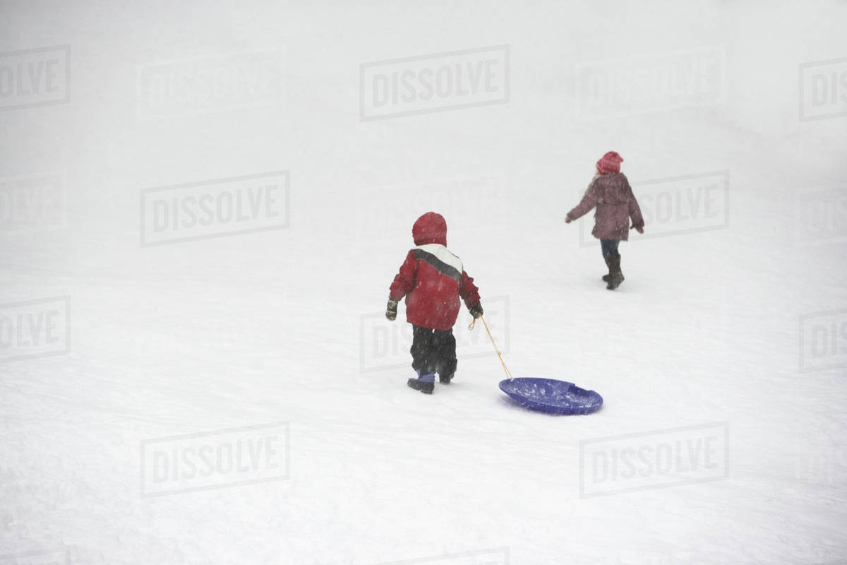 Kids pulling sled up snowy hill - Royalty-free Stock Photo | Dissolve