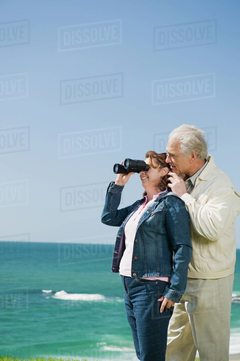 Couple looking at ocean with binoculars - Royalty-free Stock Photo ...