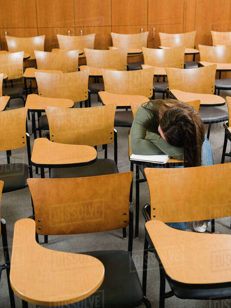 College student sleeping in empty lecture hall - Stock Photo - Dissolve