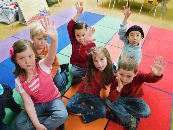 Elementary school students raising their hands - Stock Photo - Dissolve
