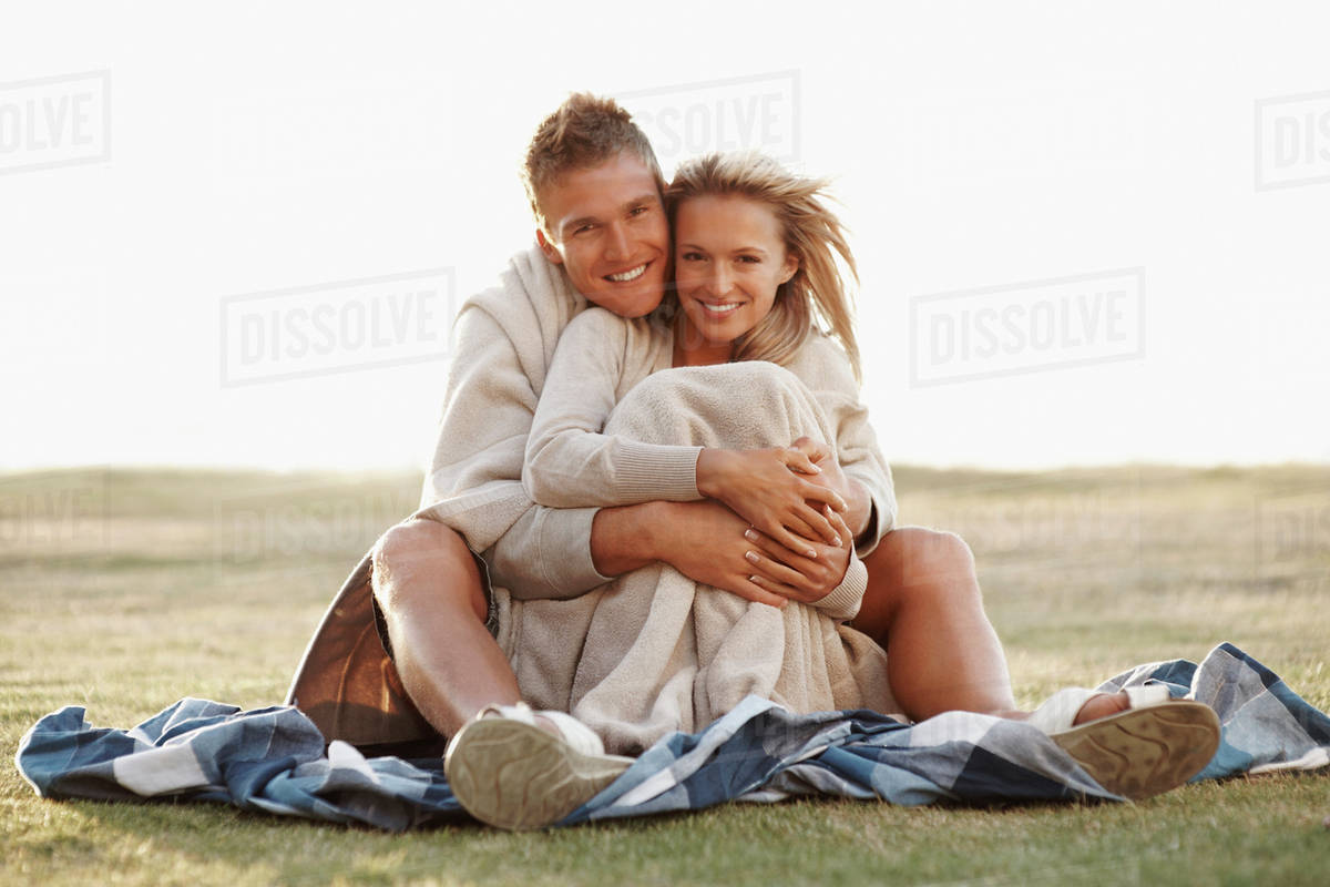 Couple sitting together in a field - Royalty-free Stock Photo | Dissolve