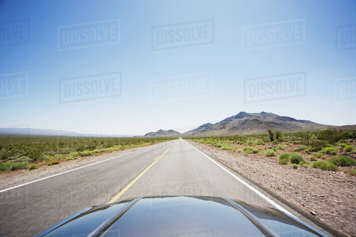 Car driving on highway through the desert - Stock Photo - Dissolve