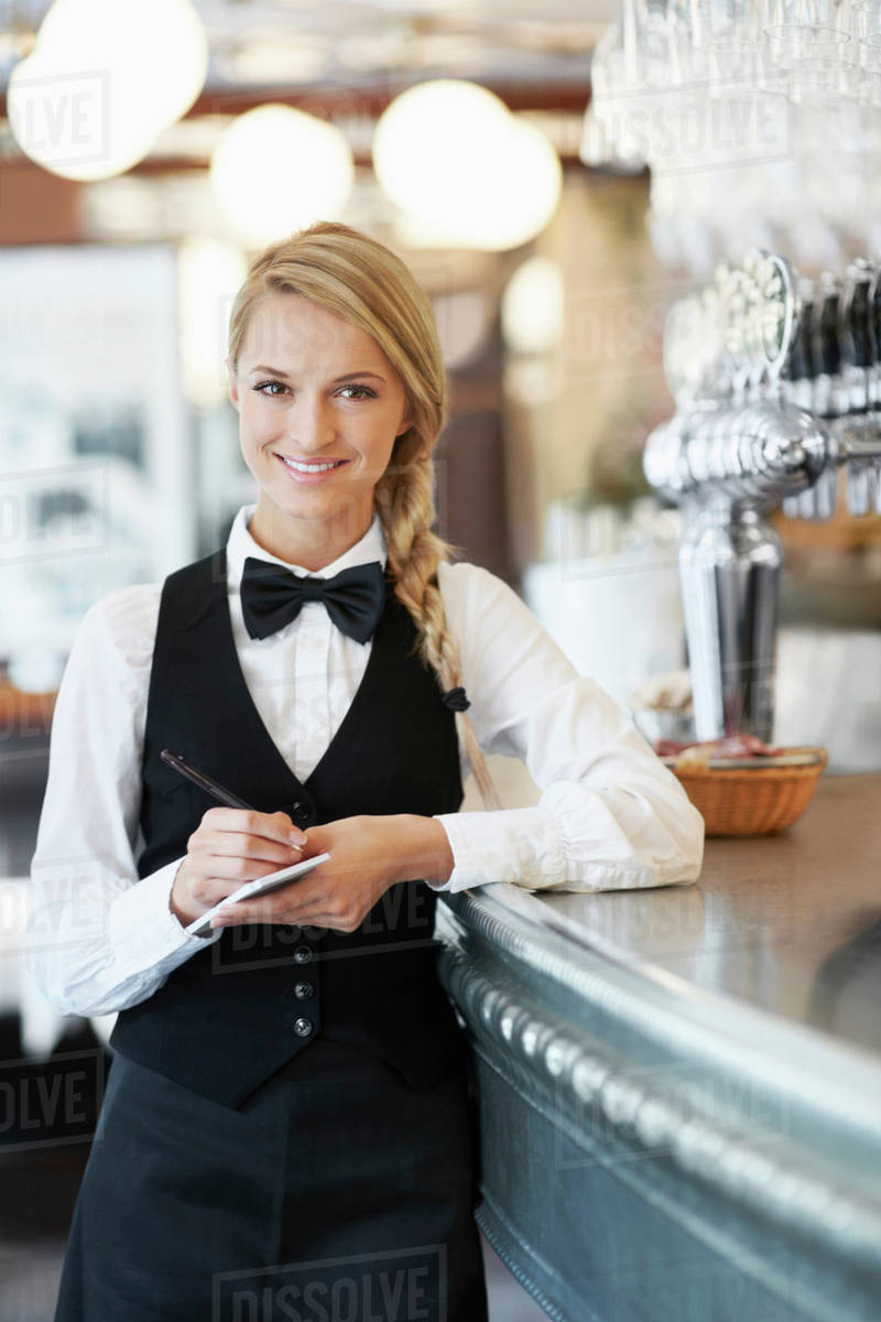 Portrait of smiling waitress standing by bar counter - Royalty-free ...