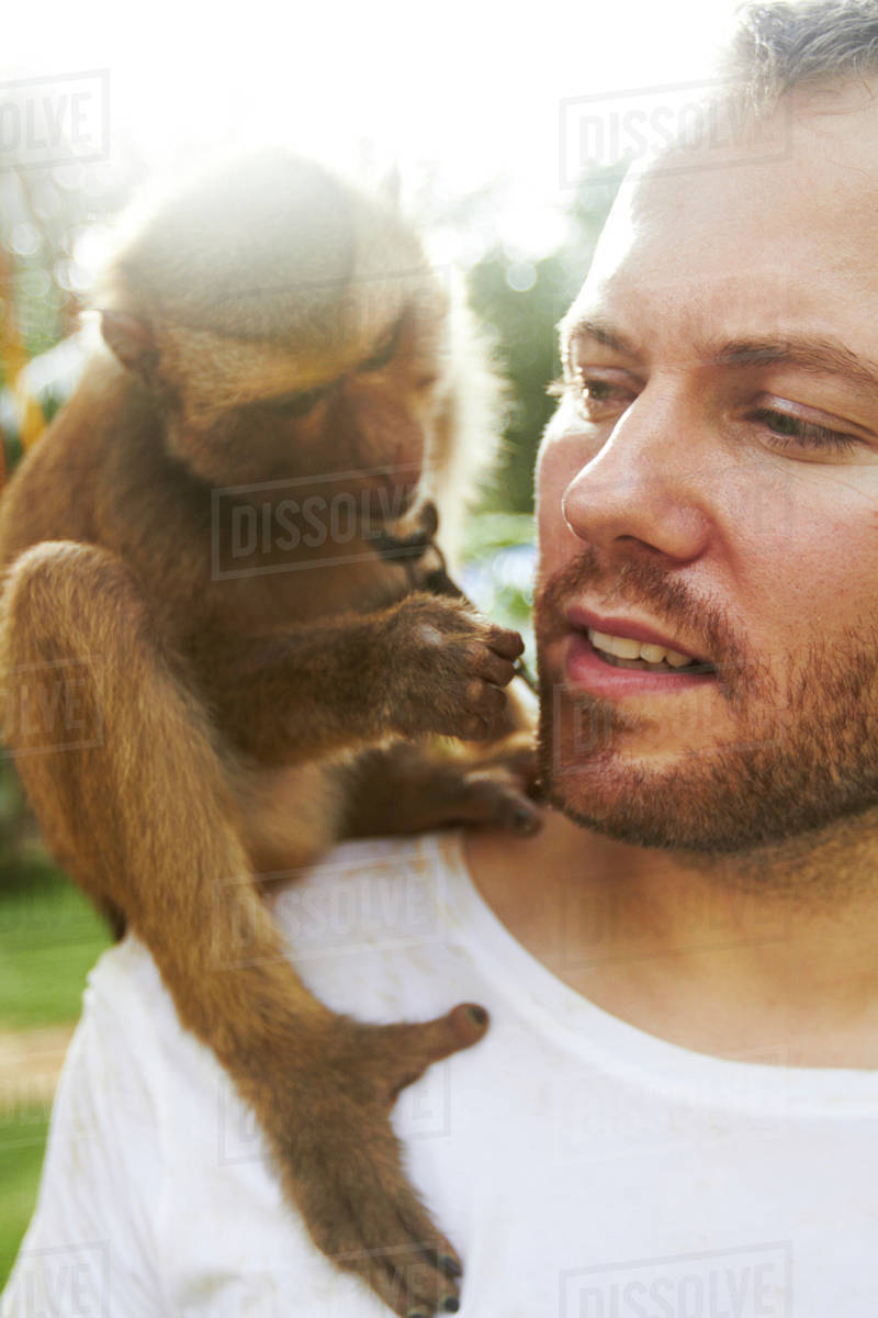 Portrait of man holding monkey - Stock Photo - Dissolve
