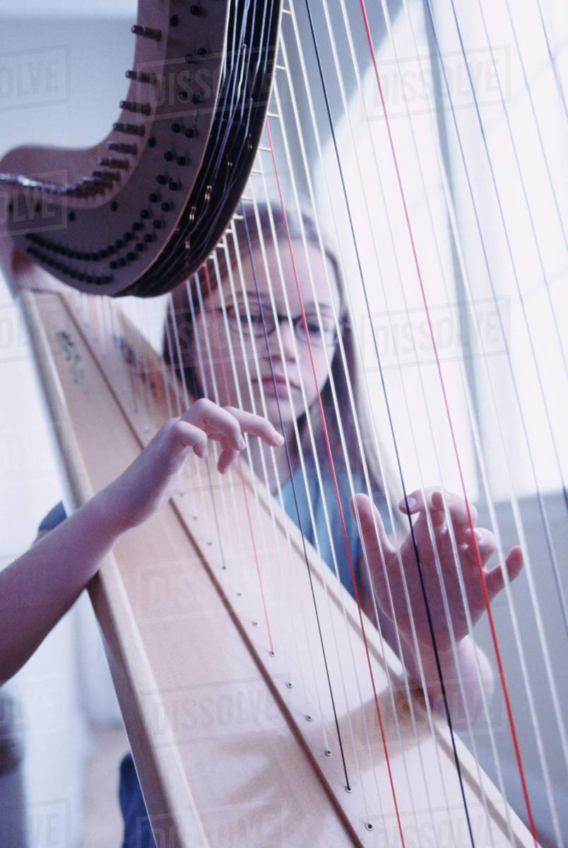 Young girl playing the harp - Royalty-free Stock Photo | Dissolve