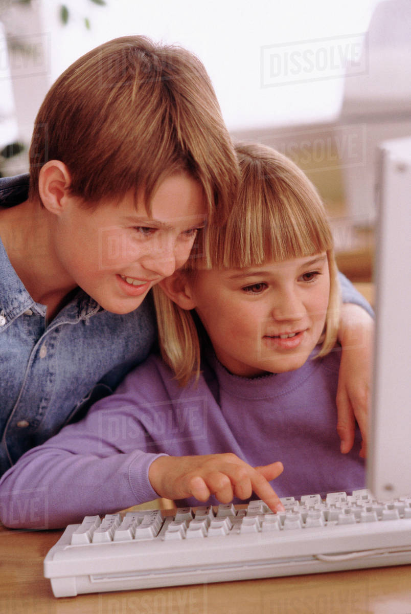 Siblings looking at computer together - Stock Photo - Dissolve