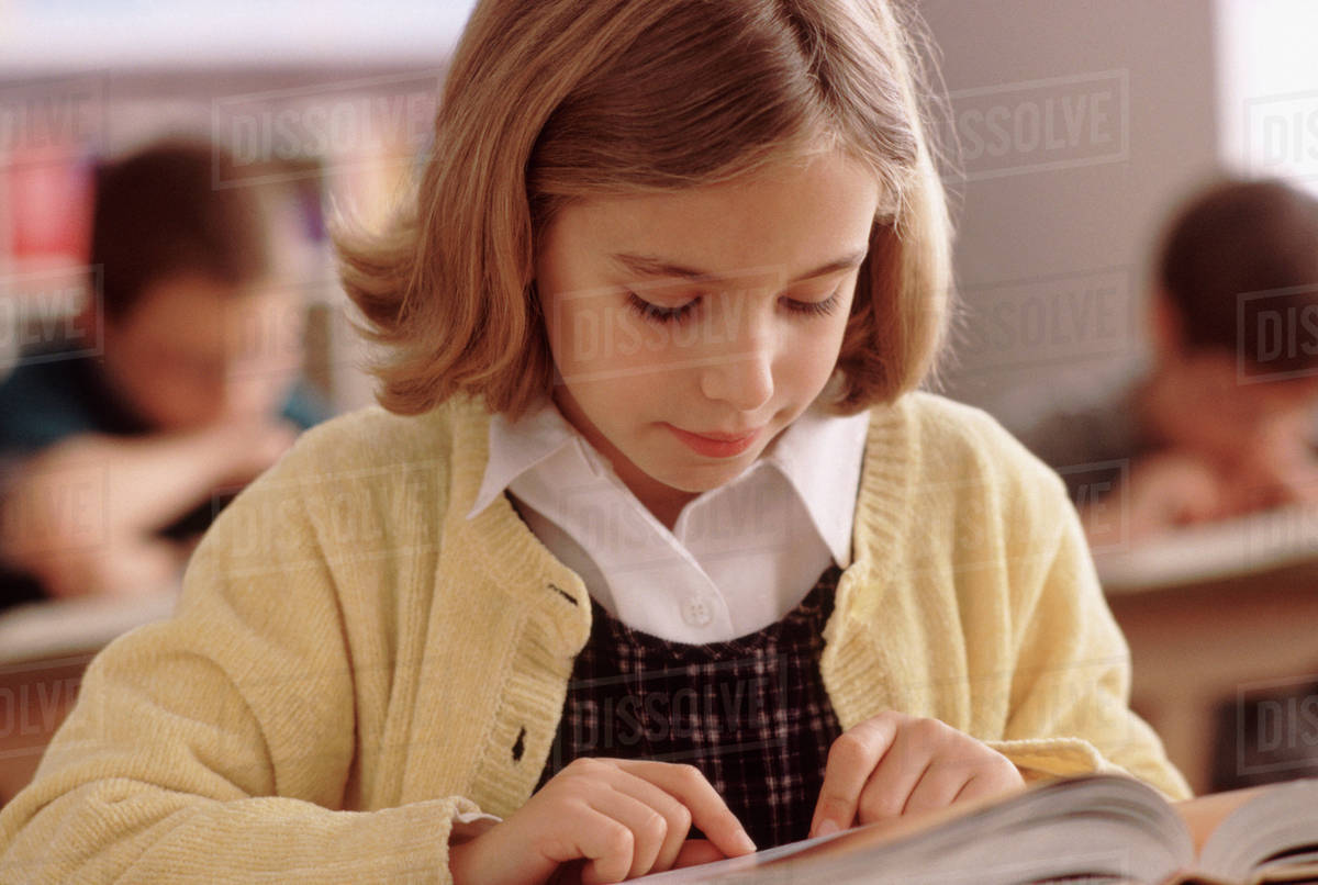 Elementary school student reading book at her desk - Royalty-free Stock ...