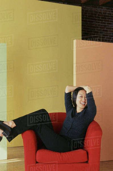 Woman relaxing in red chair - Royalty-free Stock Photo | Dissolve