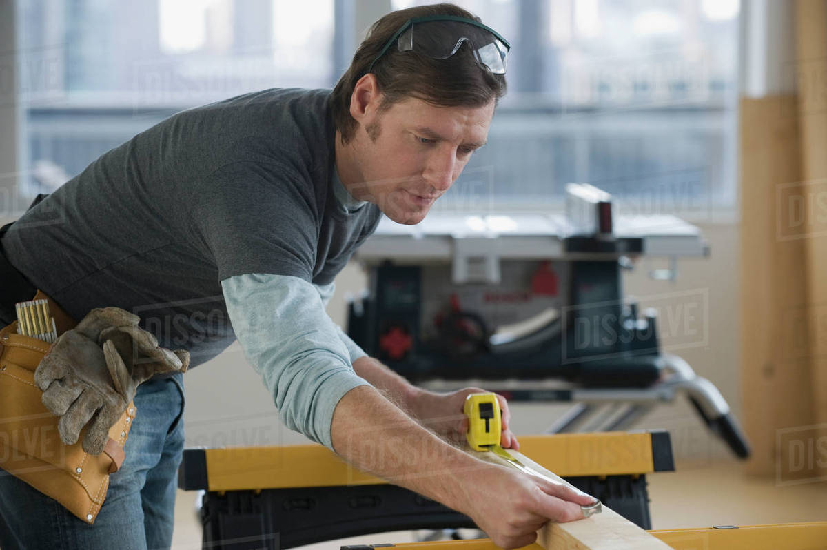 Construction worker measuring board - Royalty-free Stock Photo | Dissolve