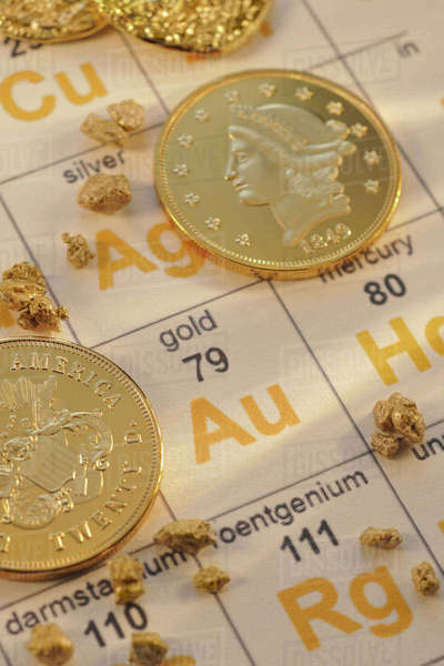 Periodic table of elements and gold coins - Stock Photo - Dissolve