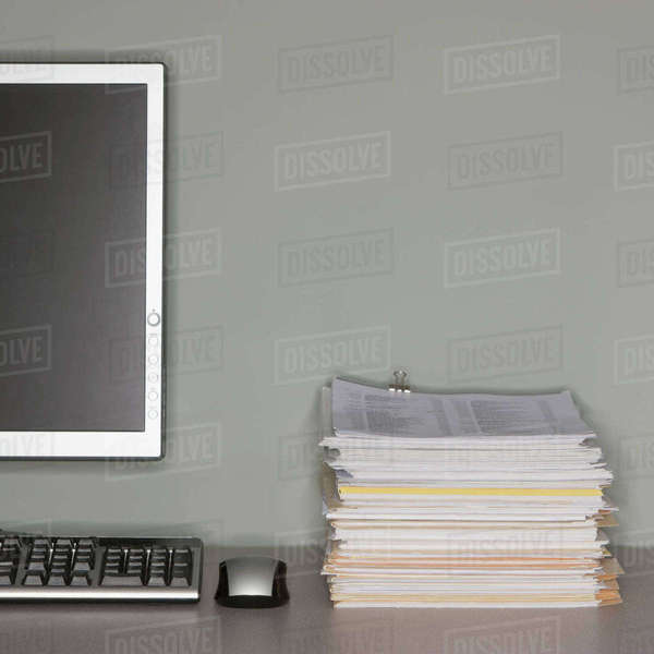 Computer and stack of paperwork - Royalty-free Stock Photo | Dissolve
