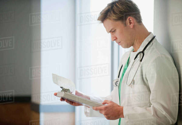 Doctor reading medical chart - Royalty-free Stock Photo | Dissolve
