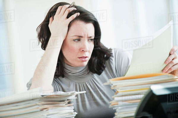 Stressed business woman reading paperwork in office - Stock Photo ...