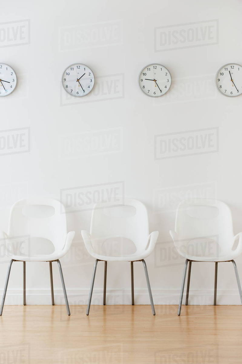 Row of chairs in waiting room under clocks displaying time zones ...