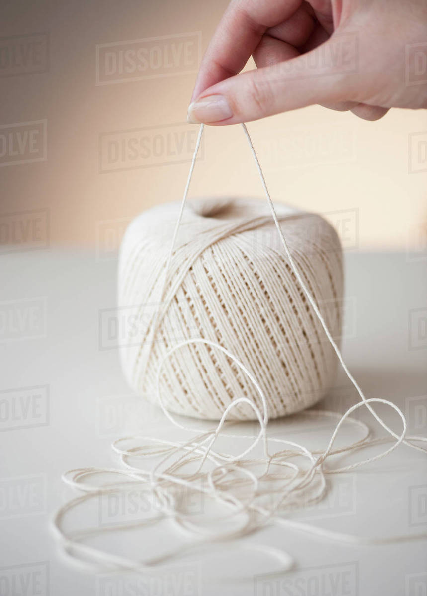Hand pulling ball of string - Stock Photo - Dissolve