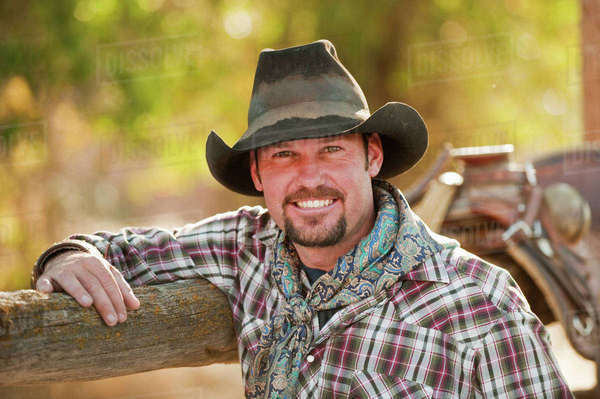 Cowboy leaning on fence - Stock Photo - Dissolve