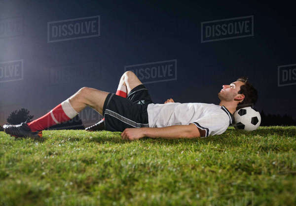 Soccer player resting on ball - Royalty-free Stock Photo | Dissolve