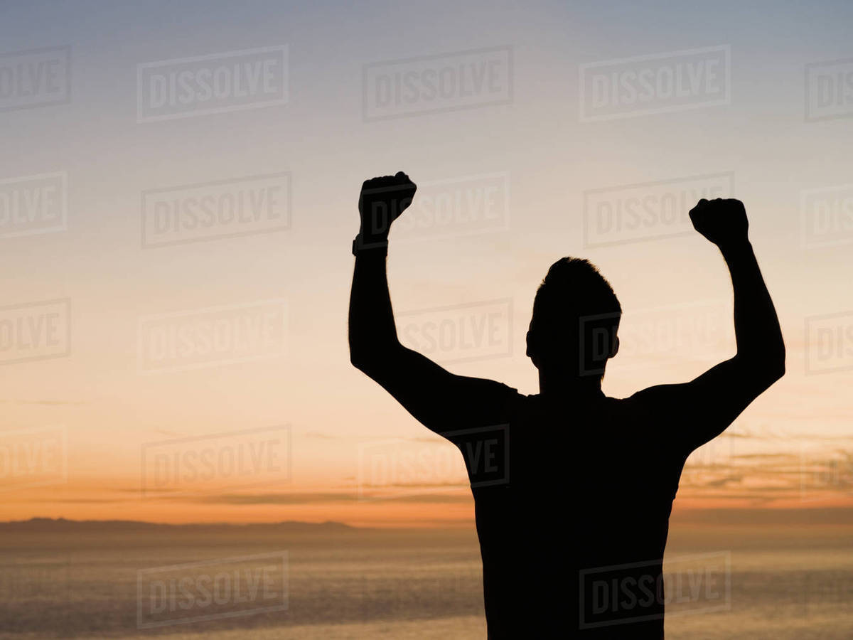 Silhouette of man raising arms - Stock Photo - Dissolve