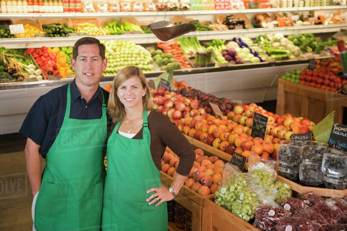 Store owners posing in produce section - Stock Photo - Dissolve
