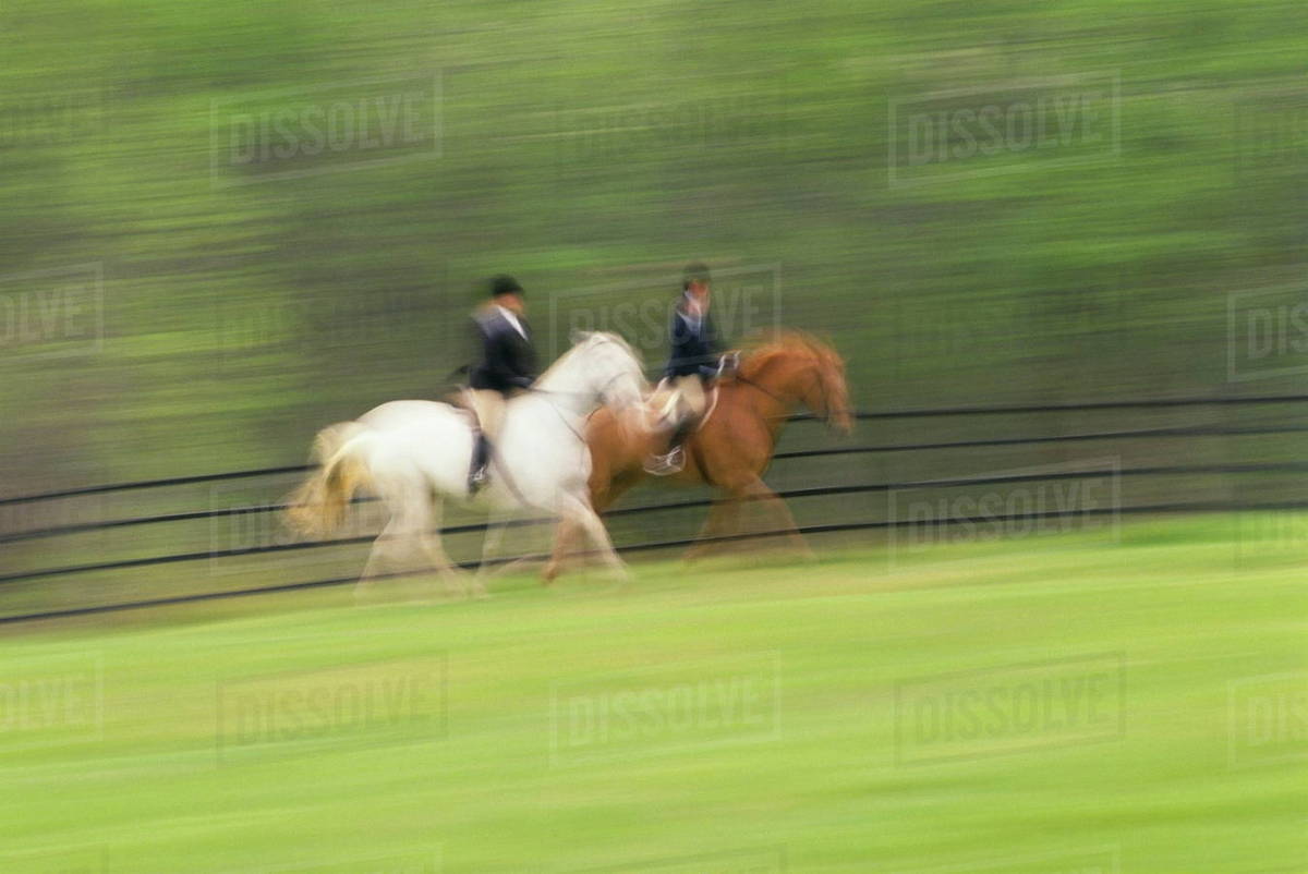 Two people riding on horses on field, blurred motion - Royalty-free ...