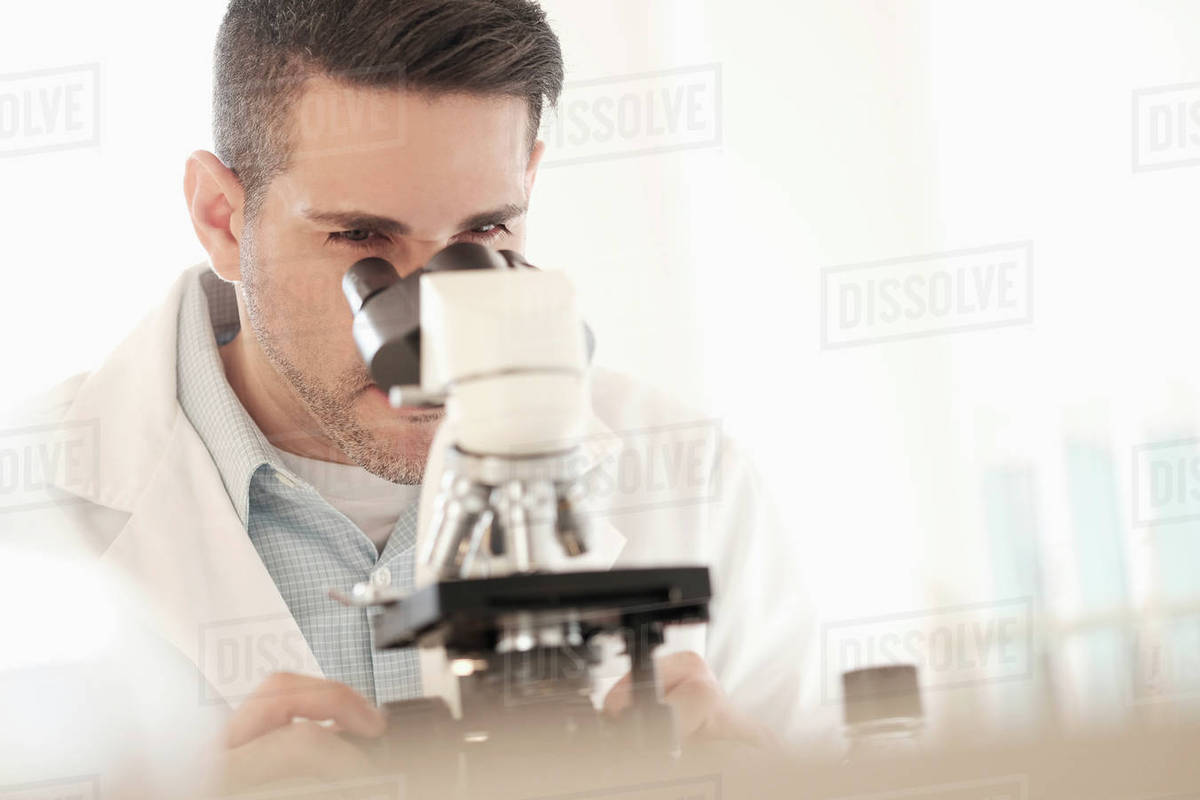 Man looking through microscope - Royalty-free Stock Photo | Dissolve