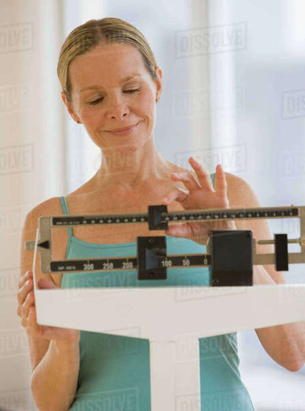 Woman weighing self on scale - Royalty-free Stock Photo | Dissolve