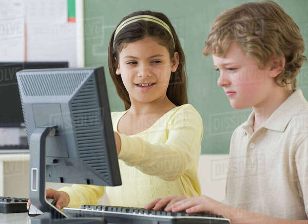 Multi-ethnic school children looking at computers - Stock Photo - Dissolve