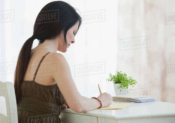 Woman writing at desk - Royalty-free Stock Photo | Dissolve