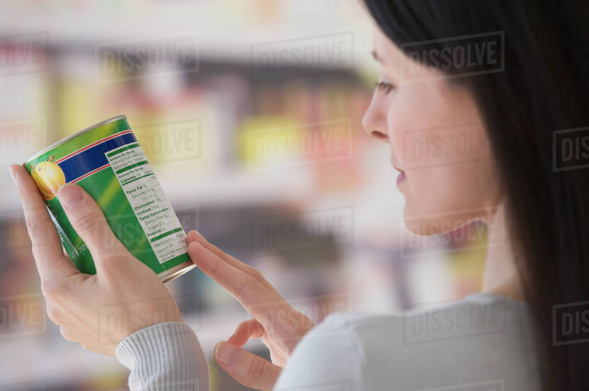 Woman reading label at grocery store - Royalty-free Stock Photo | Dissolve