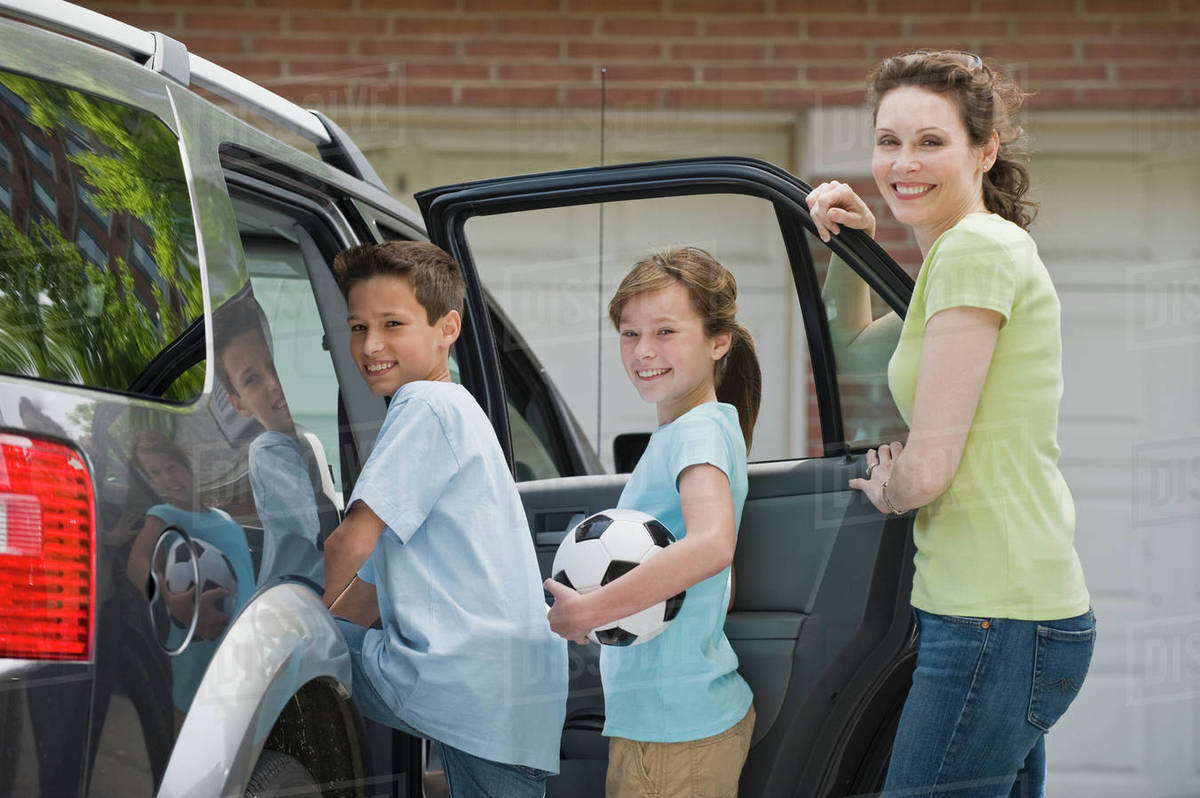 Mother and children getting into car with soccer ball - Royalty-free ...