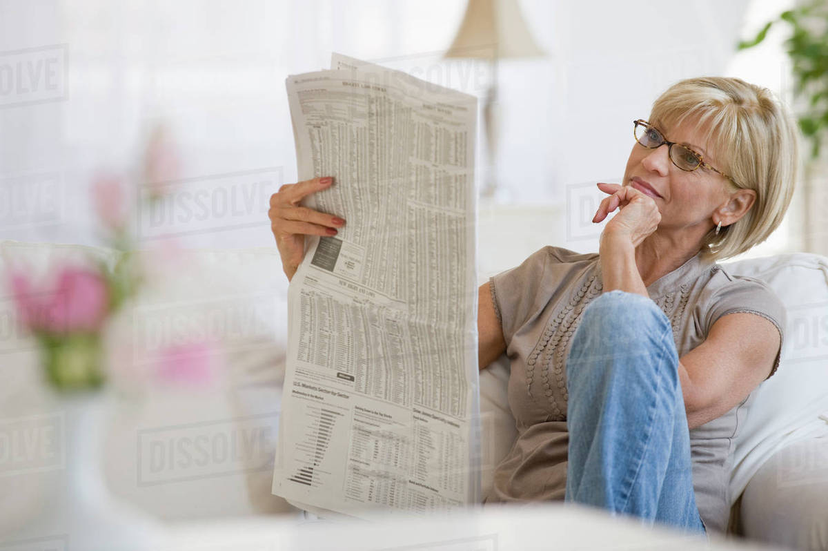 Woman reading newspaper in livingroom - Royalty-free Stock Photo | Dissolve