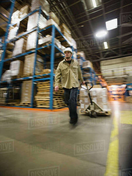 Warehouse worker pulling palette - Stock Photo - Dissolve