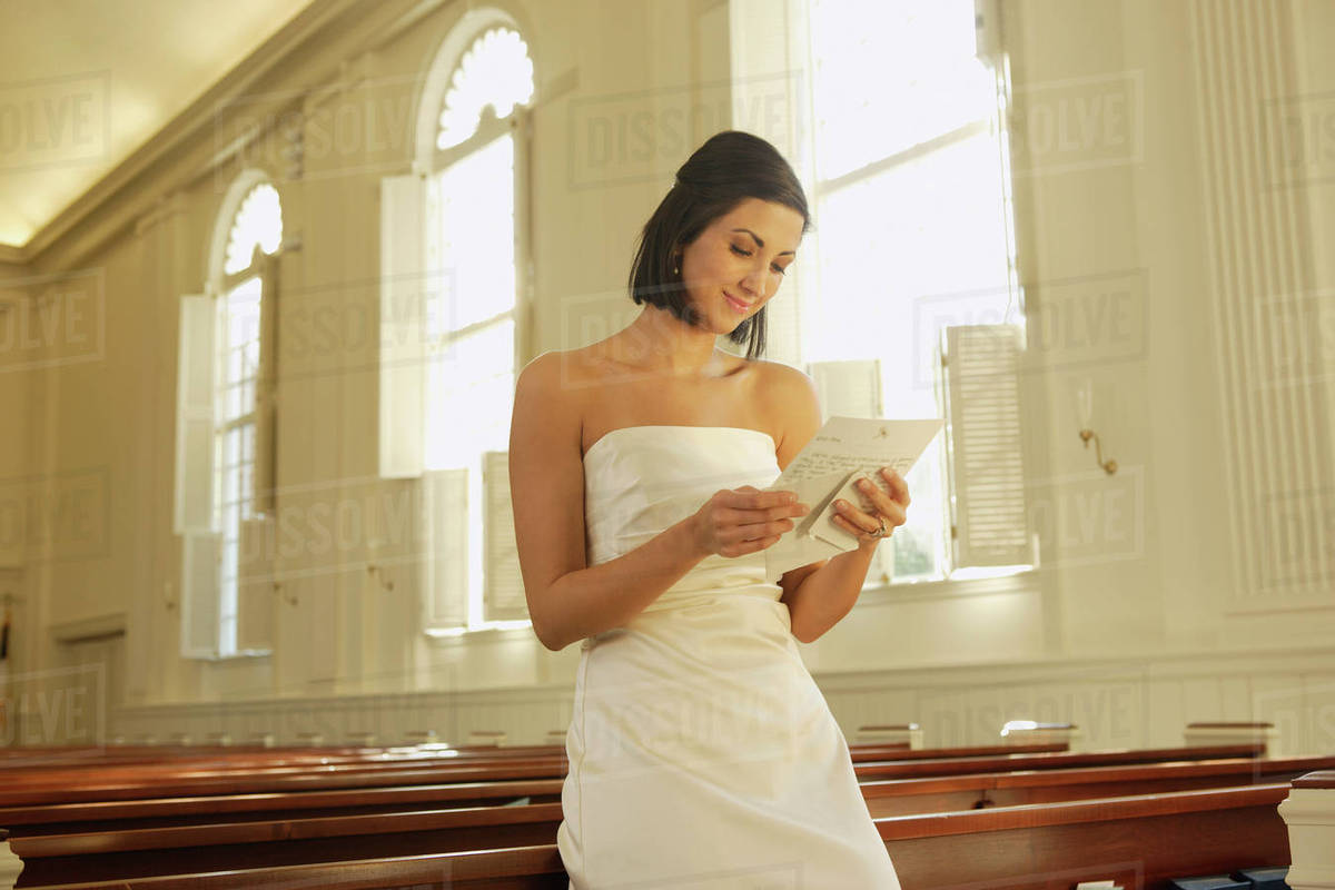 Bride reading letter in church - Royalty-free Stock Photo | Dissolve