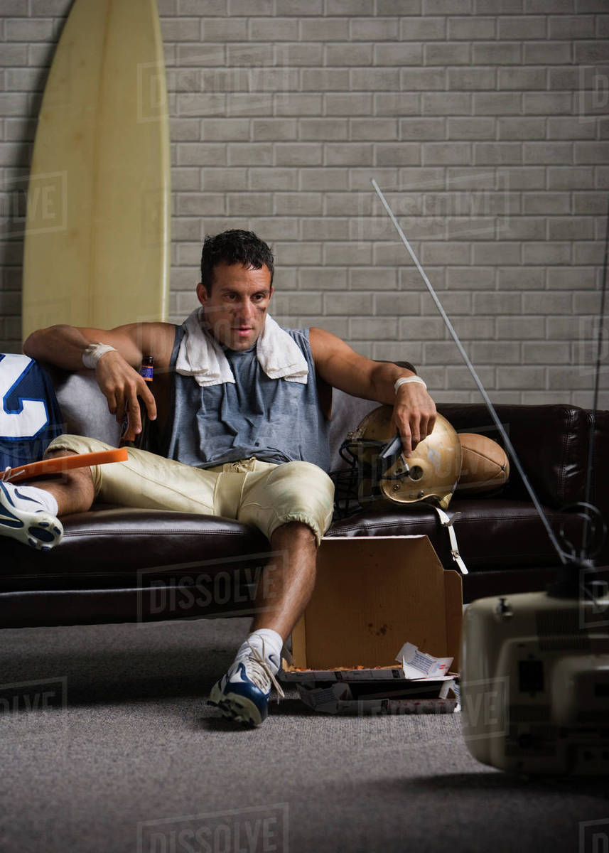 Football player watching game on sofa - Stock Photo - Dissolve