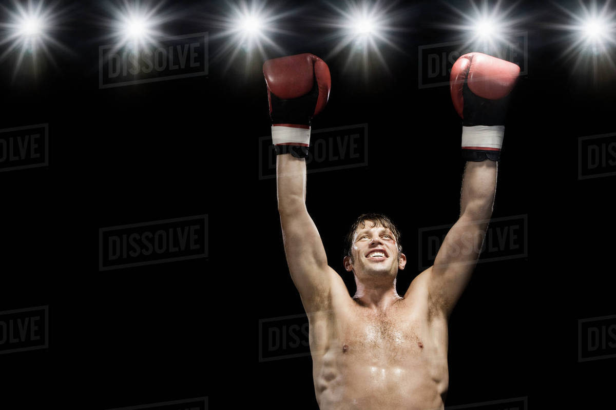 Boxer smiling with boxing gloves raised - Stock Photo - Dissolve