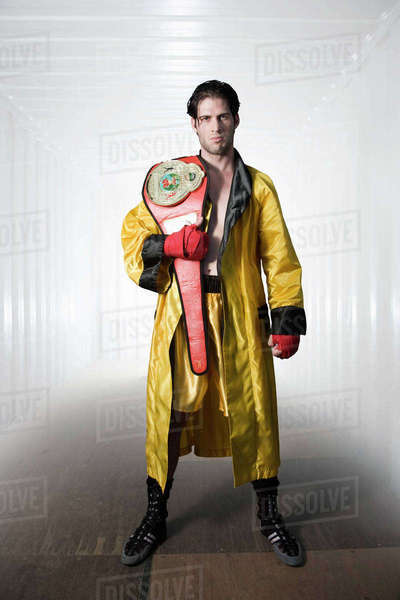 Boxer in robe posing with championship belt - Stock Photo - Dissolve