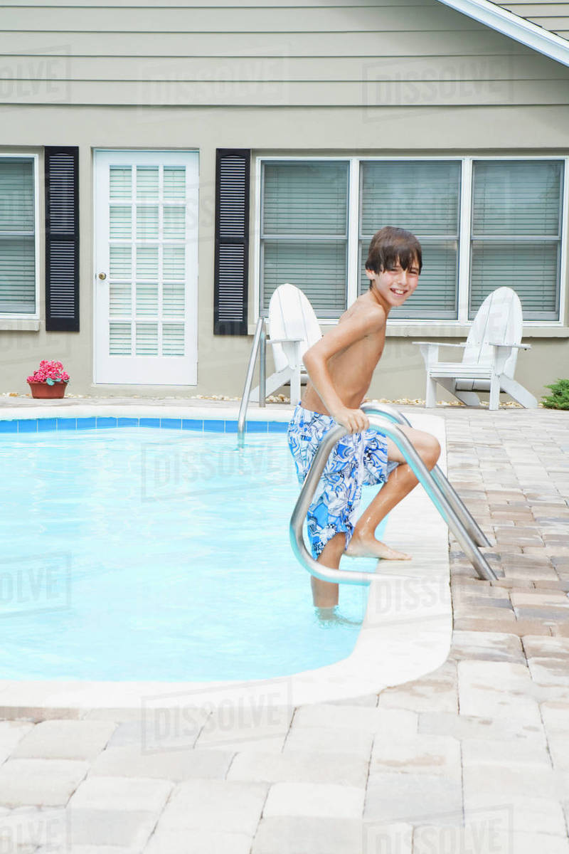 Boy stepping out of swimming pool - Stock Photo - Dissolve