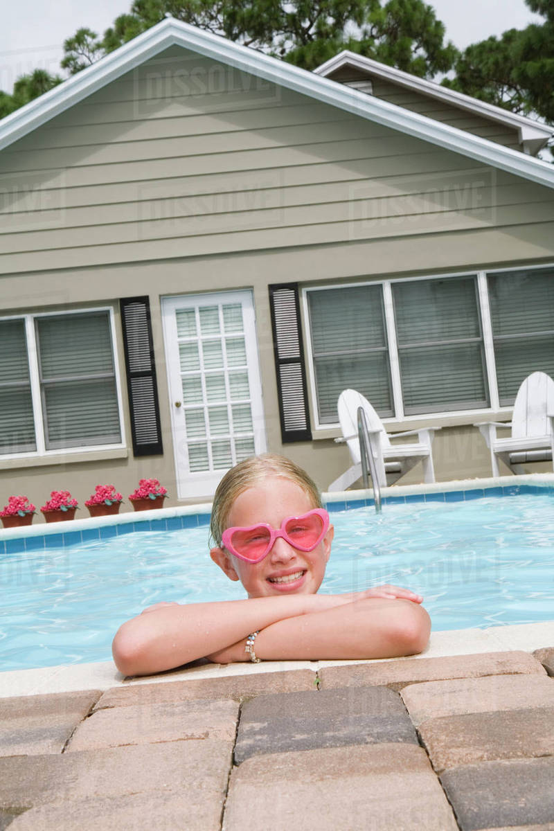 Girl leaning on edge of swimming pool - Stock Photo - Dissolve