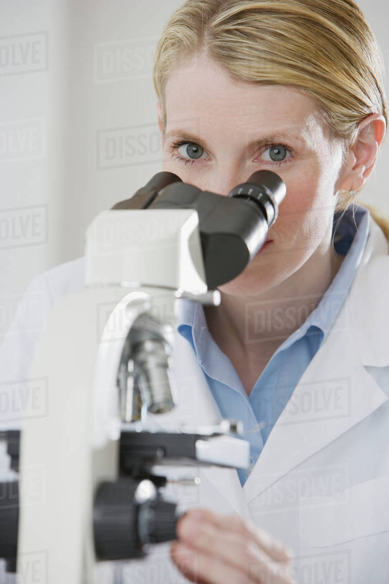 Female scientist looking into microscope - Royalty-free Stock Photo ...