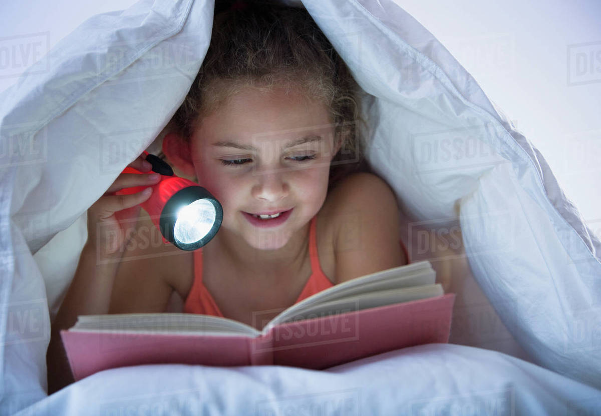 Girl reading with flashlight under blanket - Royalty-free Stock Photo ...