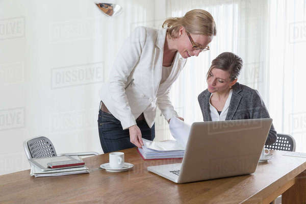 Businesswomen looking at documents at office - Stock Photo - Dissolve