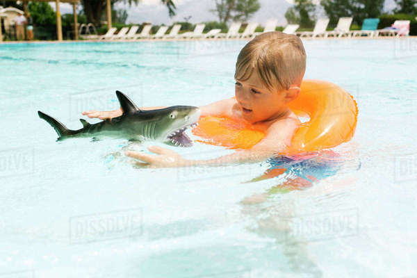 Boy (6-7) playing with toy shark in swimming pool - Royalty-free Stock ...