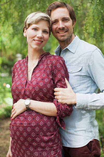 Pregnant couple embracing in garden - Stock Photo - Dissolve