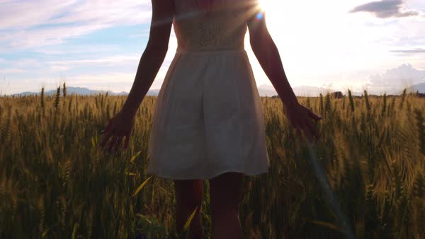 Below waist shot - Behind a girl in a white dress walking through the ...