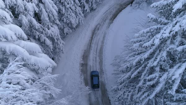 Top down view of car drifting off the snowy road in forest and gets ...