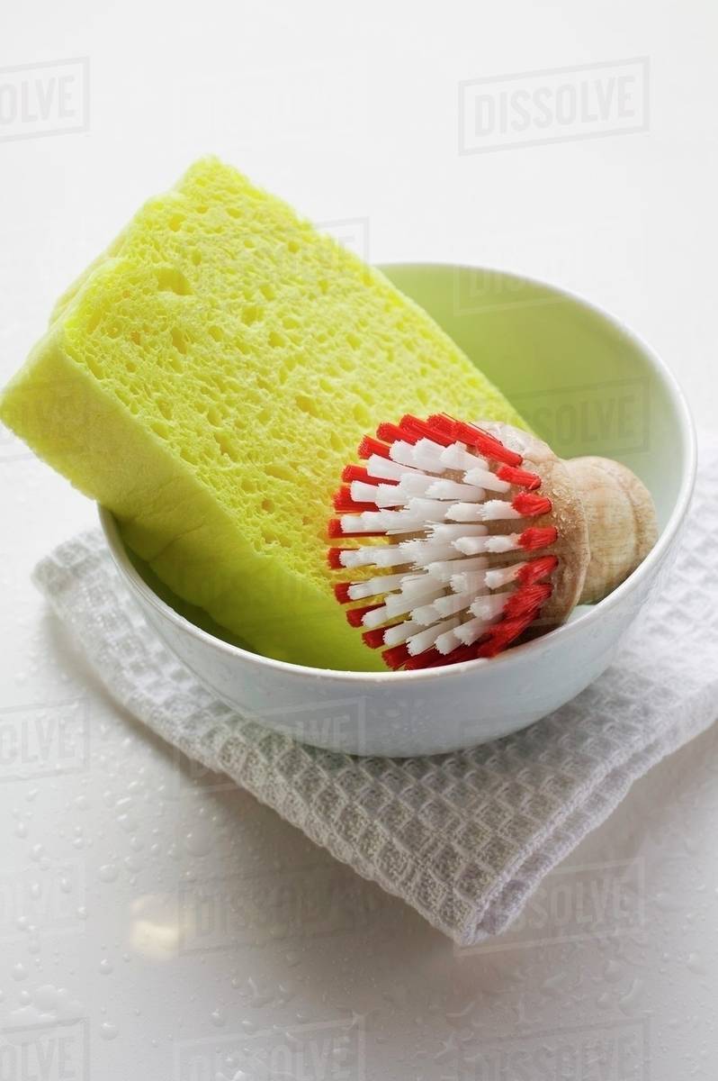 Brush and sponge in bowl on tea towel - Royalty-free Stock Photo | Dissolve