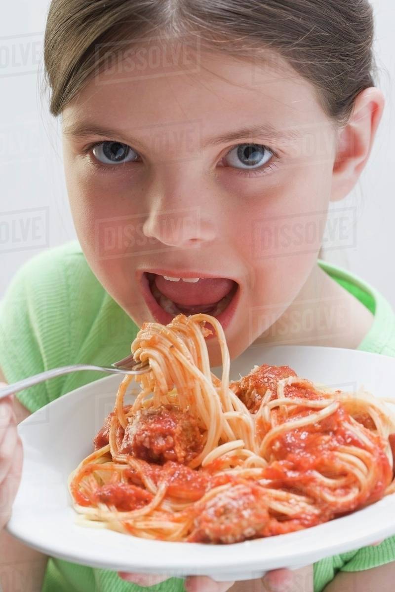 Girl eating spaghetti with meatballs - Stock Photo - Dissolve